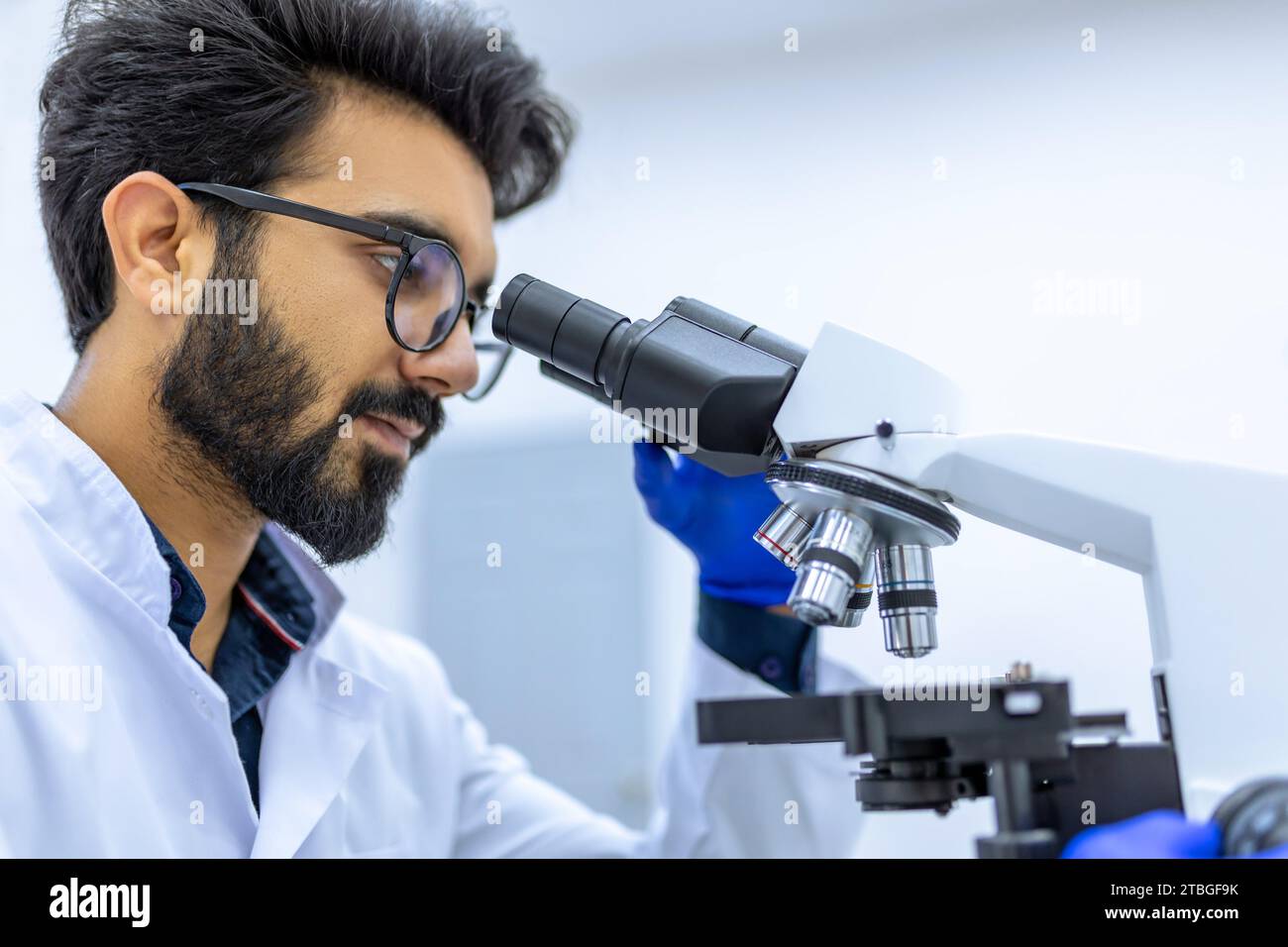 Dark haired scientist conducts experiments, adjusts specimen in petri ...