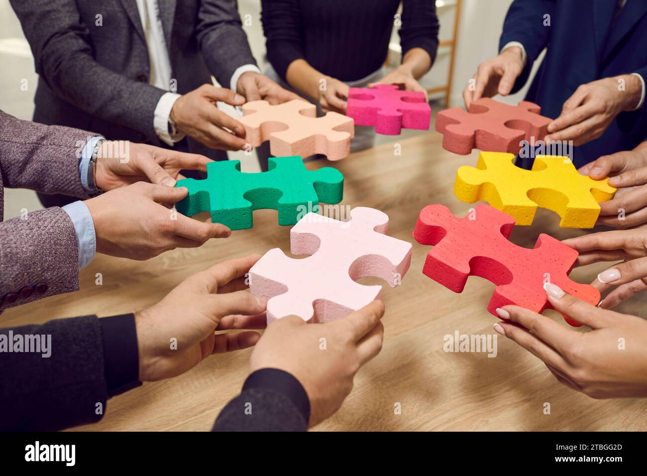 Team of office workers connecting pieces of a jigsaw puzzle to ...