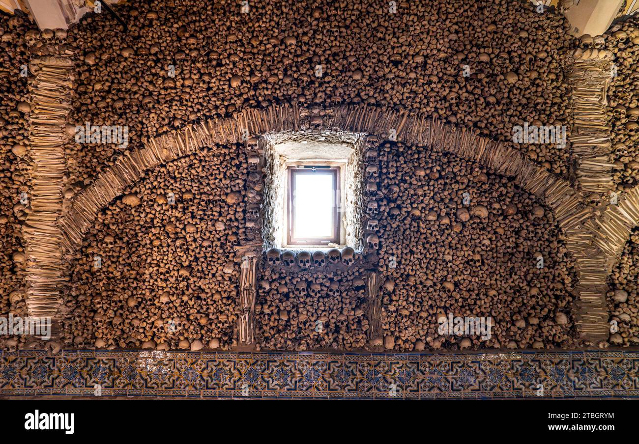 Wall decorated with stacked human skulls and an arch created with bones ...