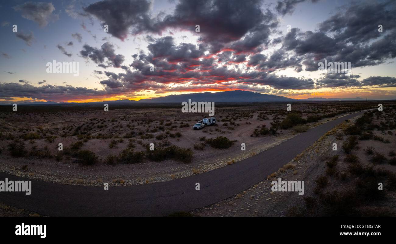 A panoramic aerial view of an RV camper parked in a desert at sunset in ...
