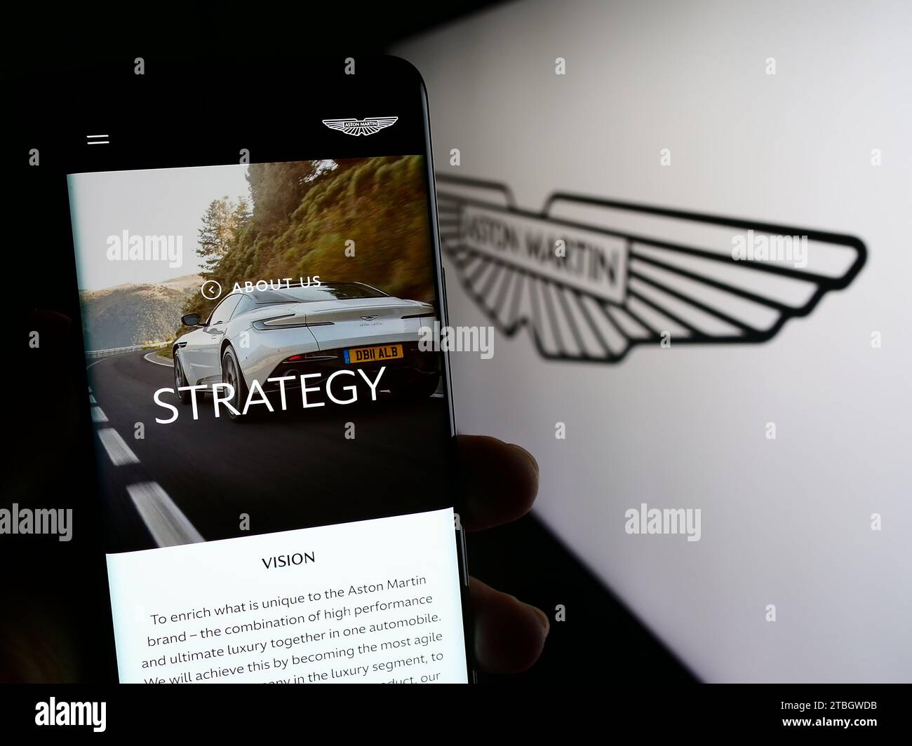Person holding cellphone with web page of British company Aston Martin Lagonda Global Holdings ...