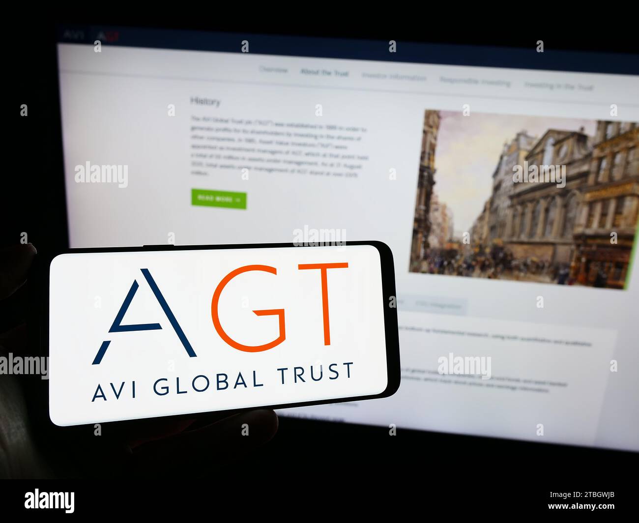 Person holding cellphone with logo of British investment company AVI Global Trust plc (AGT) in ...