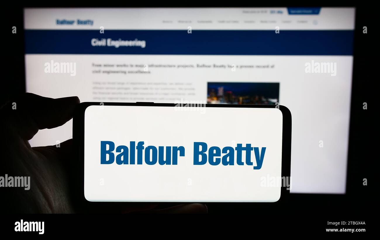 Person holding cellphone with logo of British infrastructure company Balfour Beatty plc in front ...