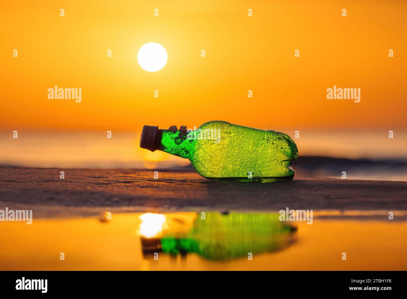 Sea sunrise and alcohol bottle on the beach sand, travel destination ...