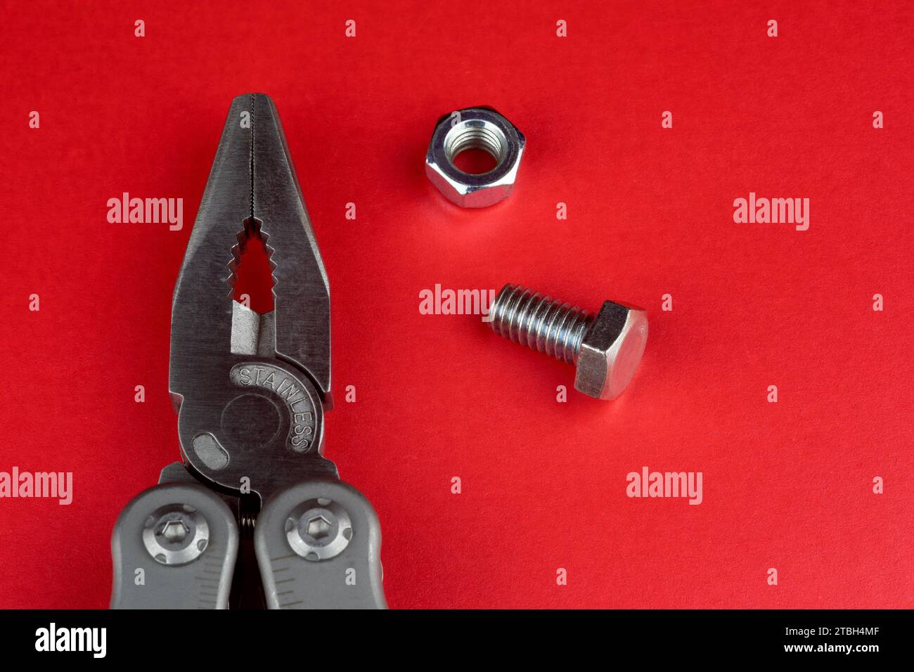 Multi Tool pliers on a red table top with nut and bolt Stock Photo - Alamy