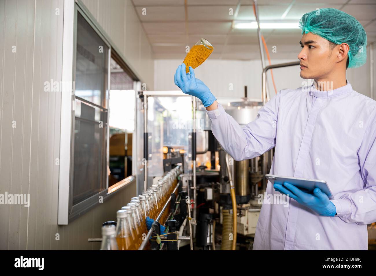 Quality control officer inspects beverage bottling factory line with ...