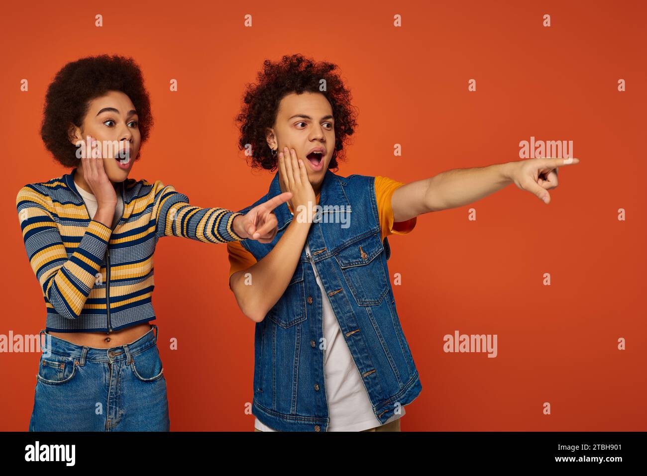 shocked african american siblings in casual attires pointing somewhere ...
