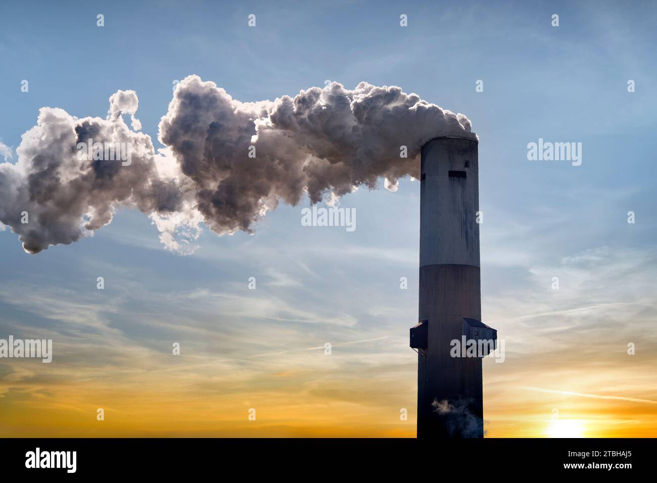 A view of an industrial plant with a large chimney emitting smoke into ...