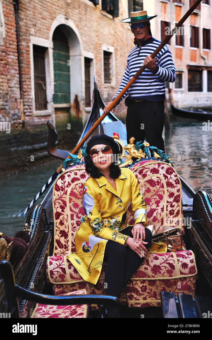Venice, Italy, a glamorous woman takes a gondola ride through the ...