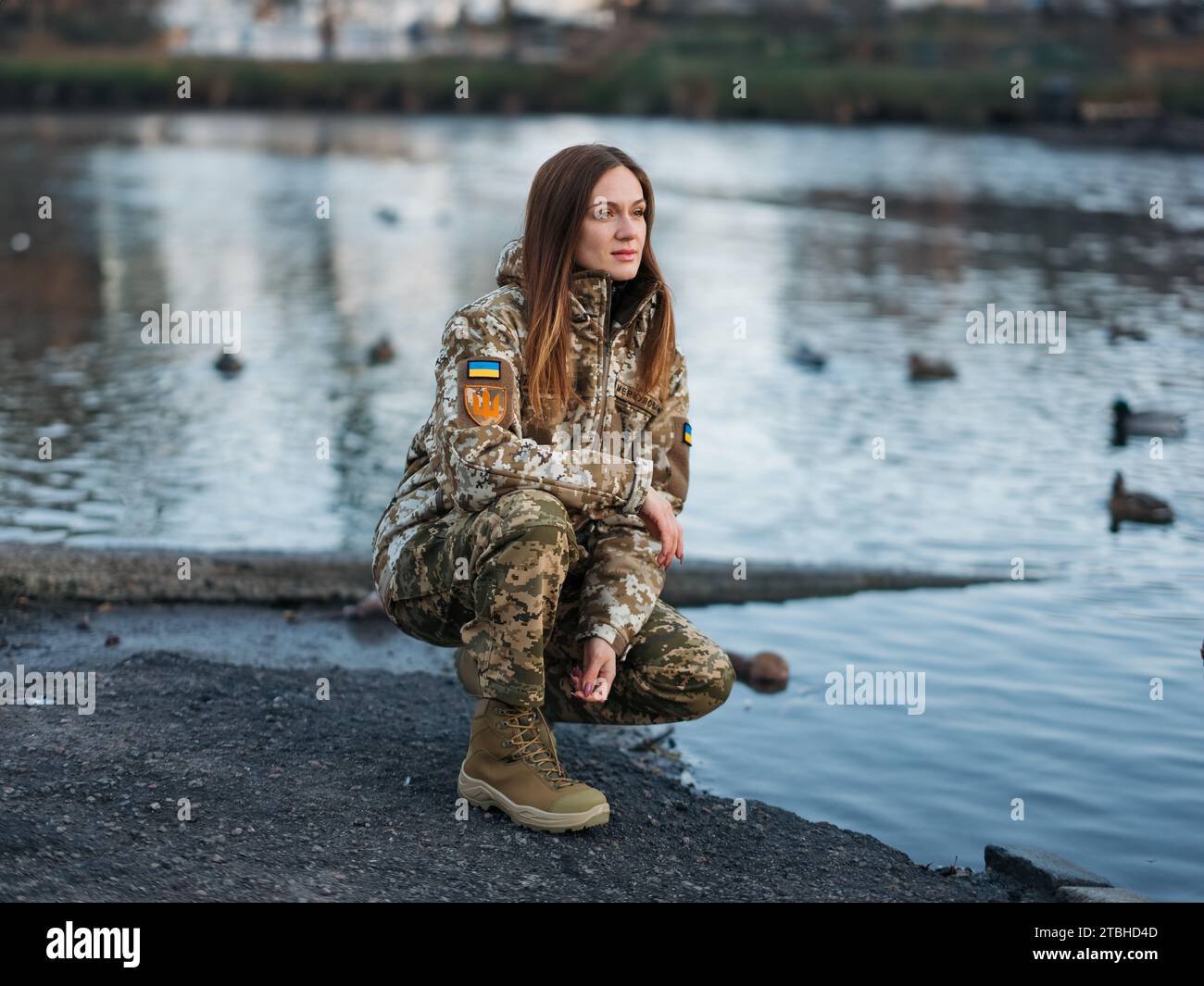 Ukrainian woman soldier resting in park during vacation near lake. Women and war. War in Ukraine ...