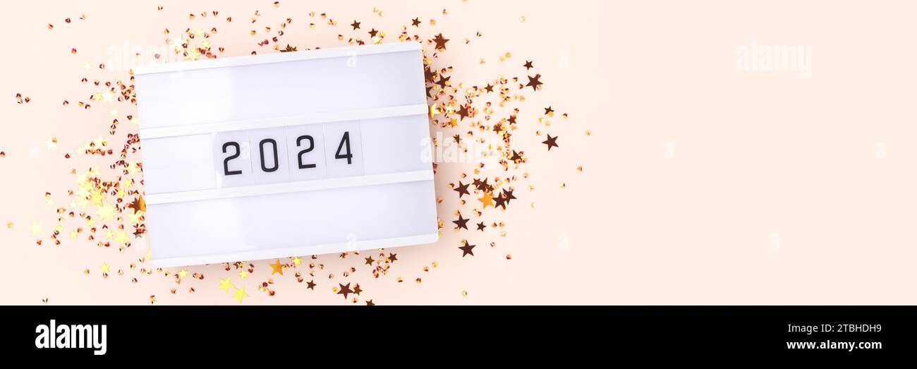 Lightbox with 2024 numbers and golden stars confetti on a beige ...