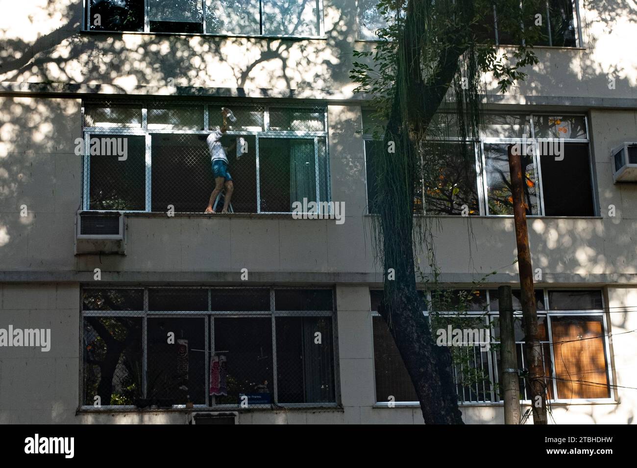 A maid stretches her body out of the window on the second floor of a ...
