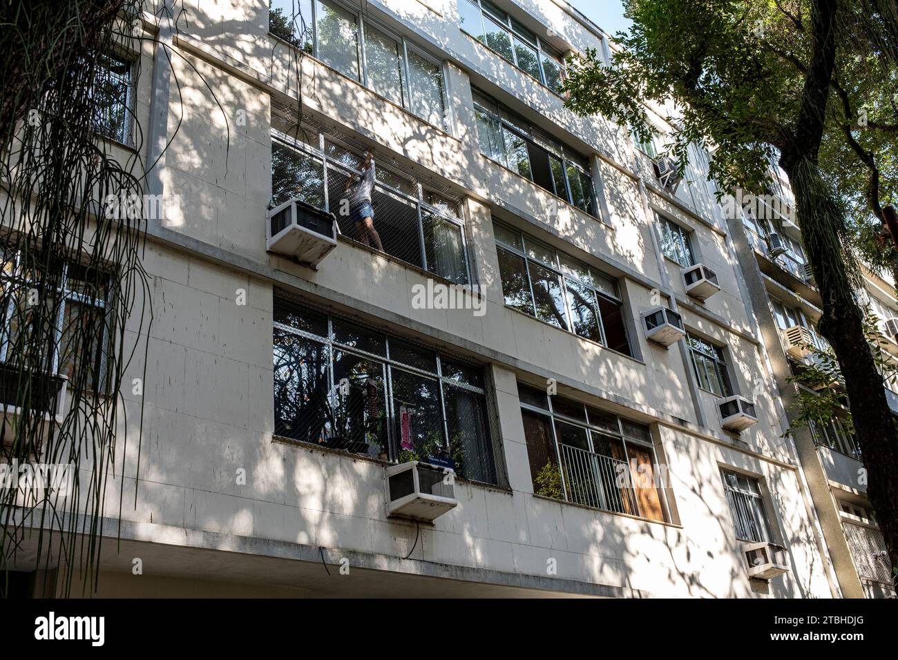 A maid stretches her body out of the window on the second floor of a ...