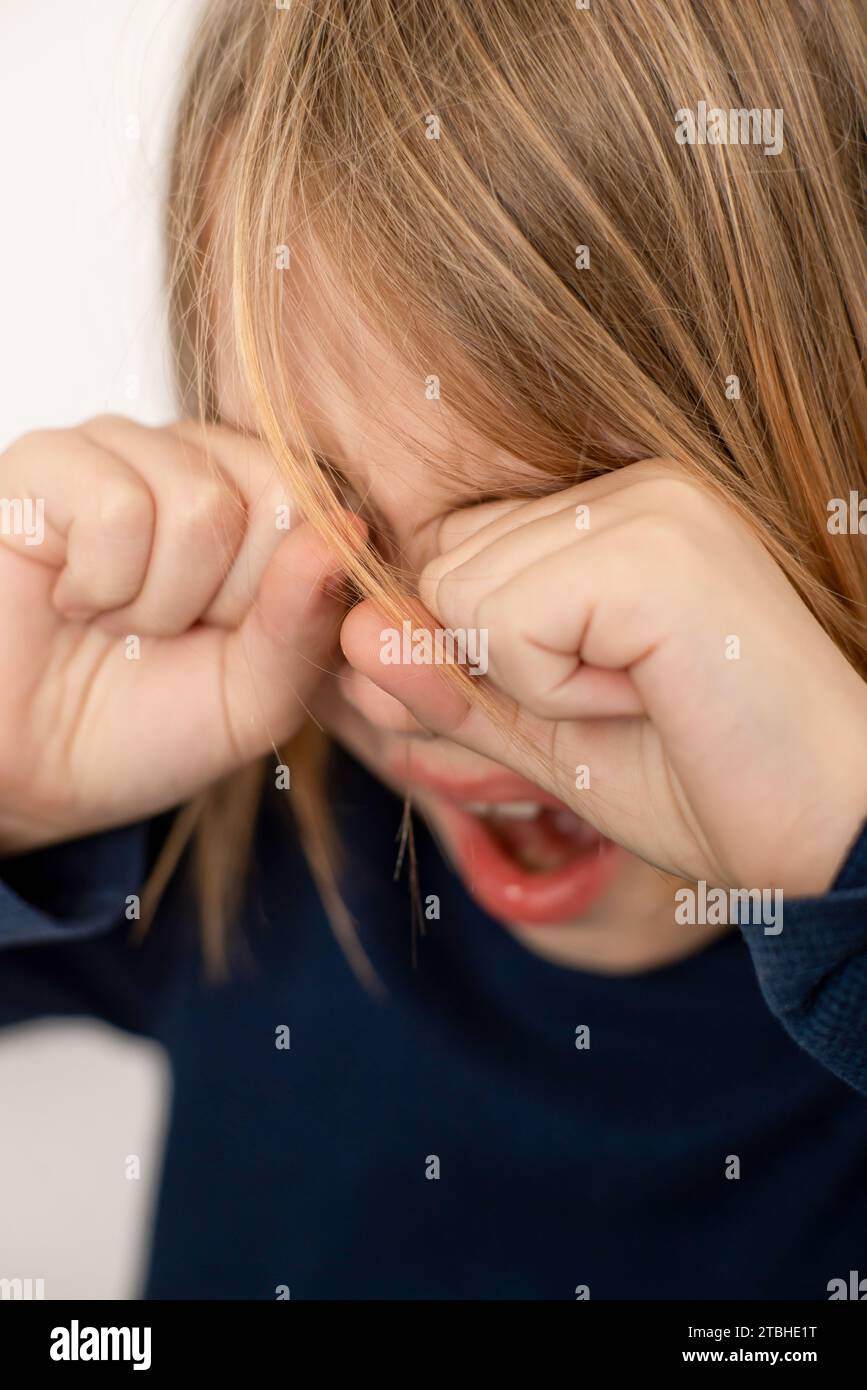 A fatigued young boy with long hair looks weary and sleep-deprived ...
