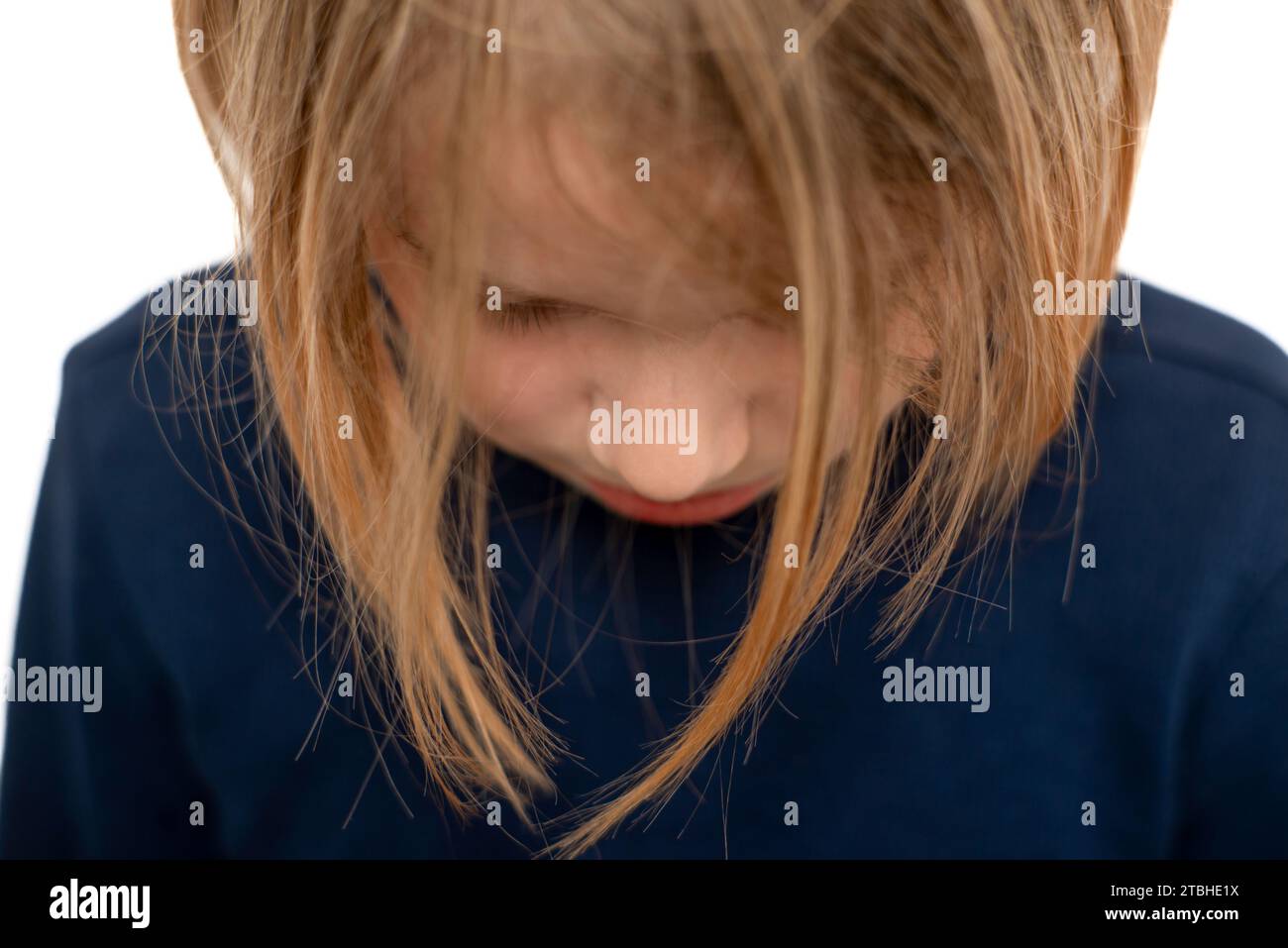 young boy with long hair lowered his head on a white background Stock ...
