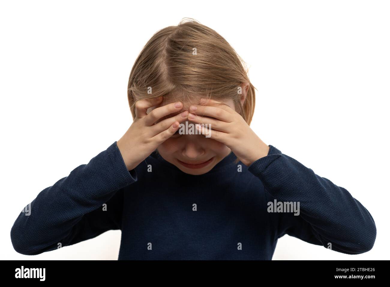 Young boy deep in thought, holding his head in his hands, captured in a ...