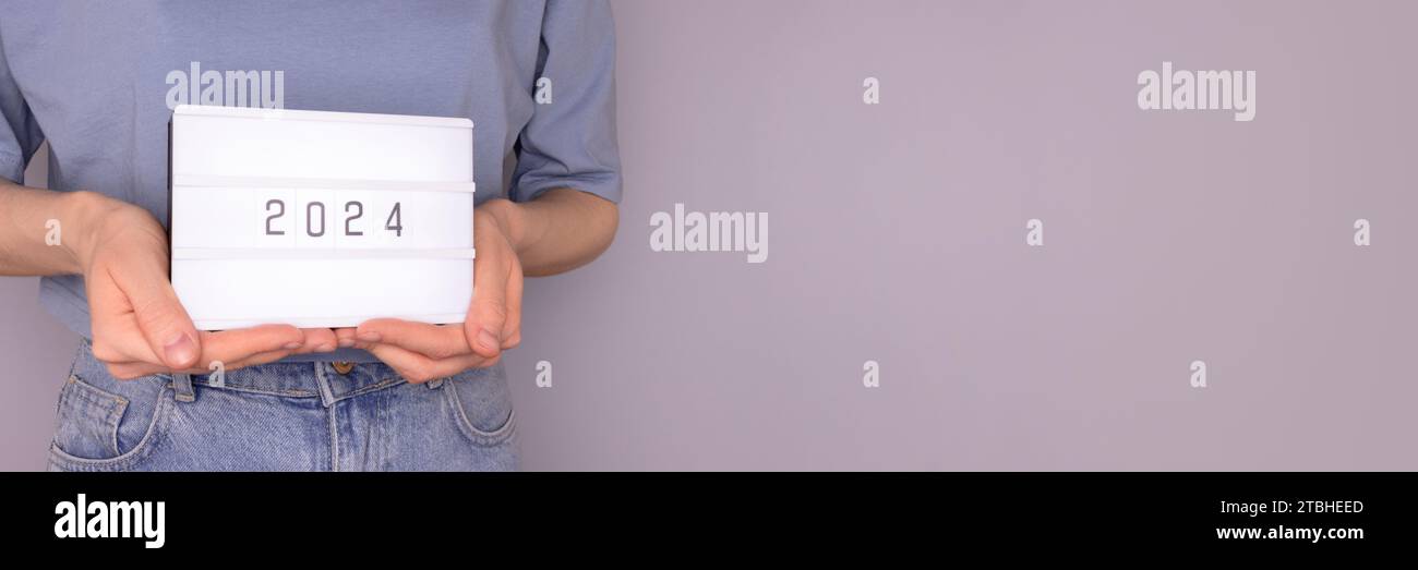 Banner with hands hold lightbox with 2024 numbers in front of blue ...