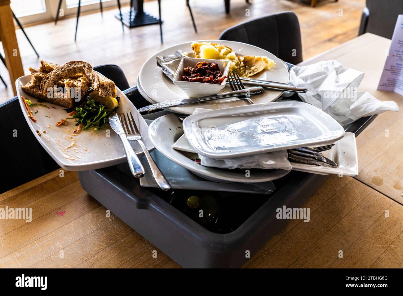 The remains of food and dirty dishes piled in a tray ready to be ...