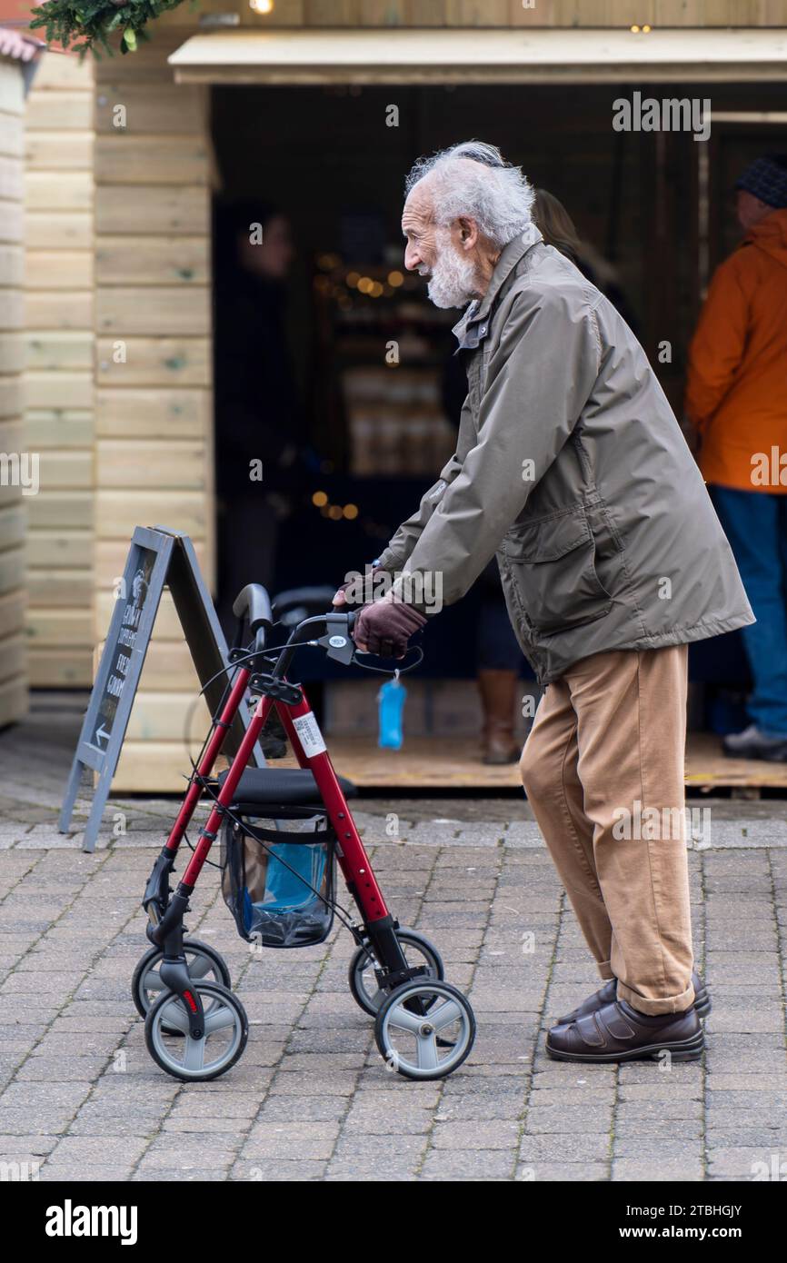 An elderly man using a wheeled walking aid rollator walking through ...