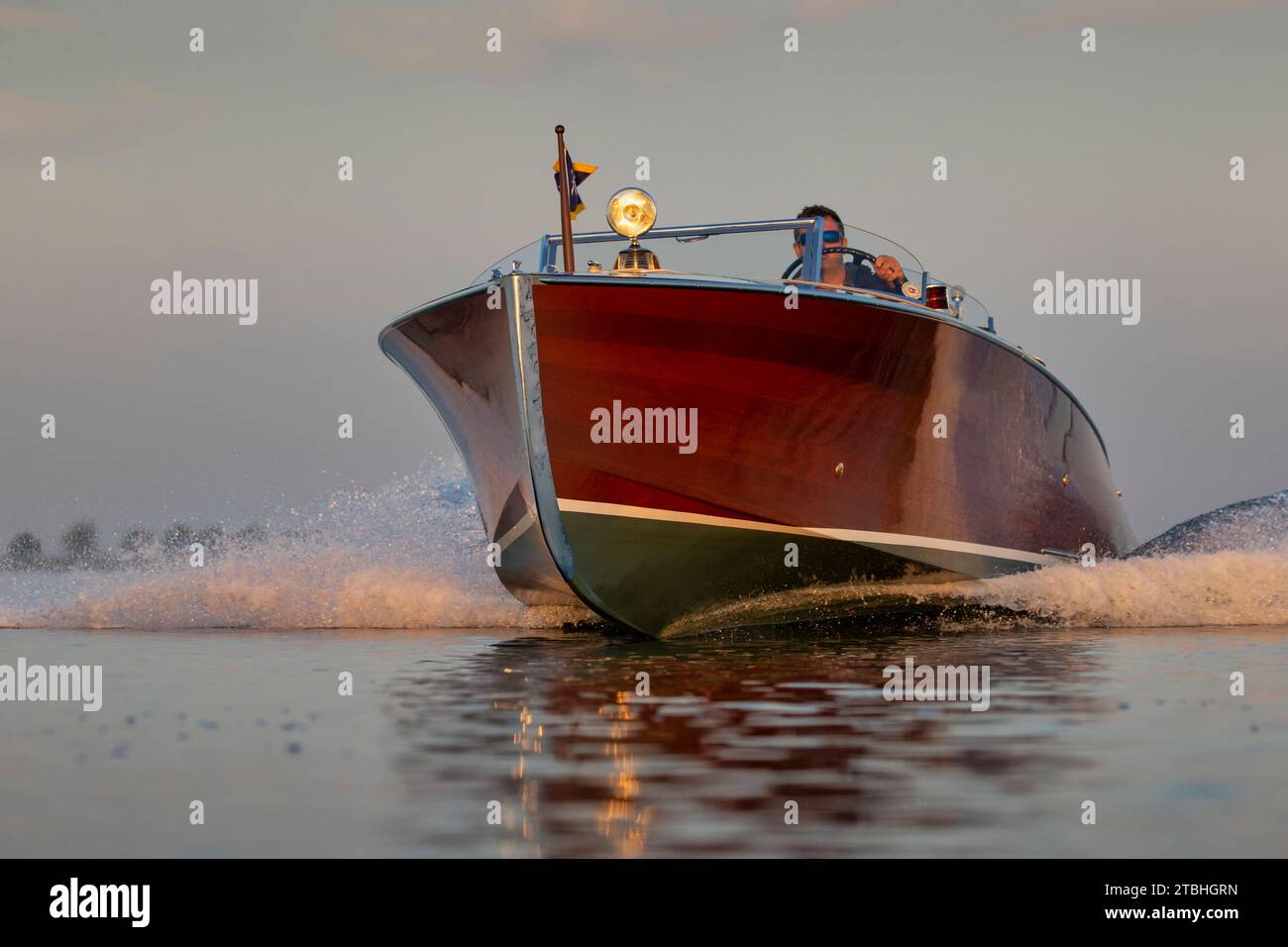 Low angle image of an antique, wood speedboat at high speed on a calm ...