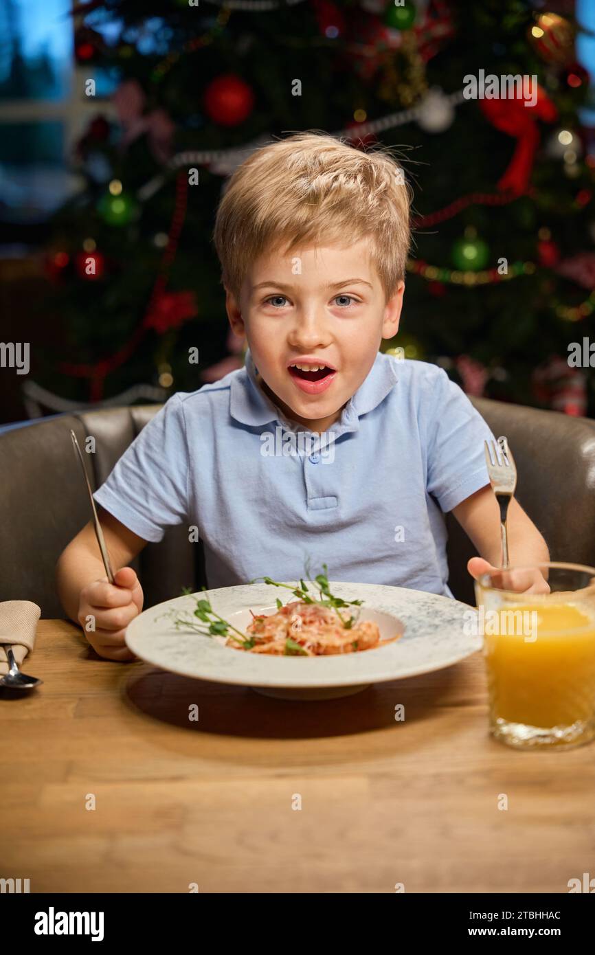 Surprised little boy eating festive meal during Christmas dinner in ...