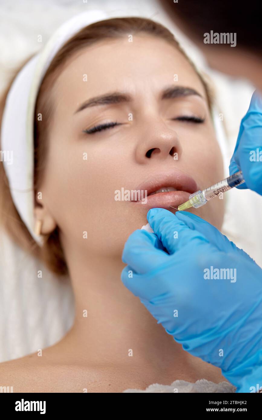 cosmetologist makes injections to enlarge the lips of beautiful woman ...