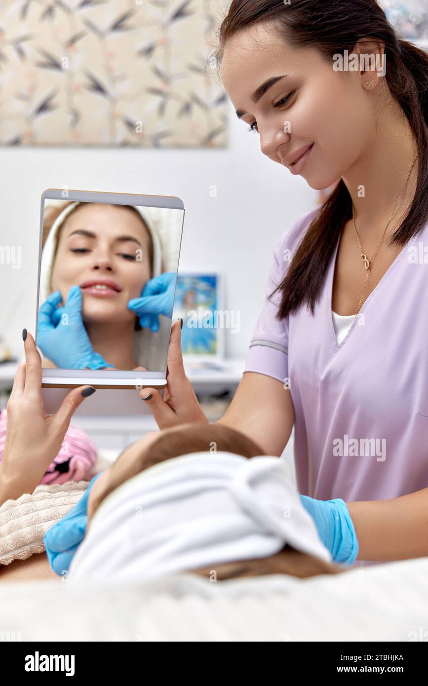 Beautiful woman looks at herself in the mirror after procedure lip ...