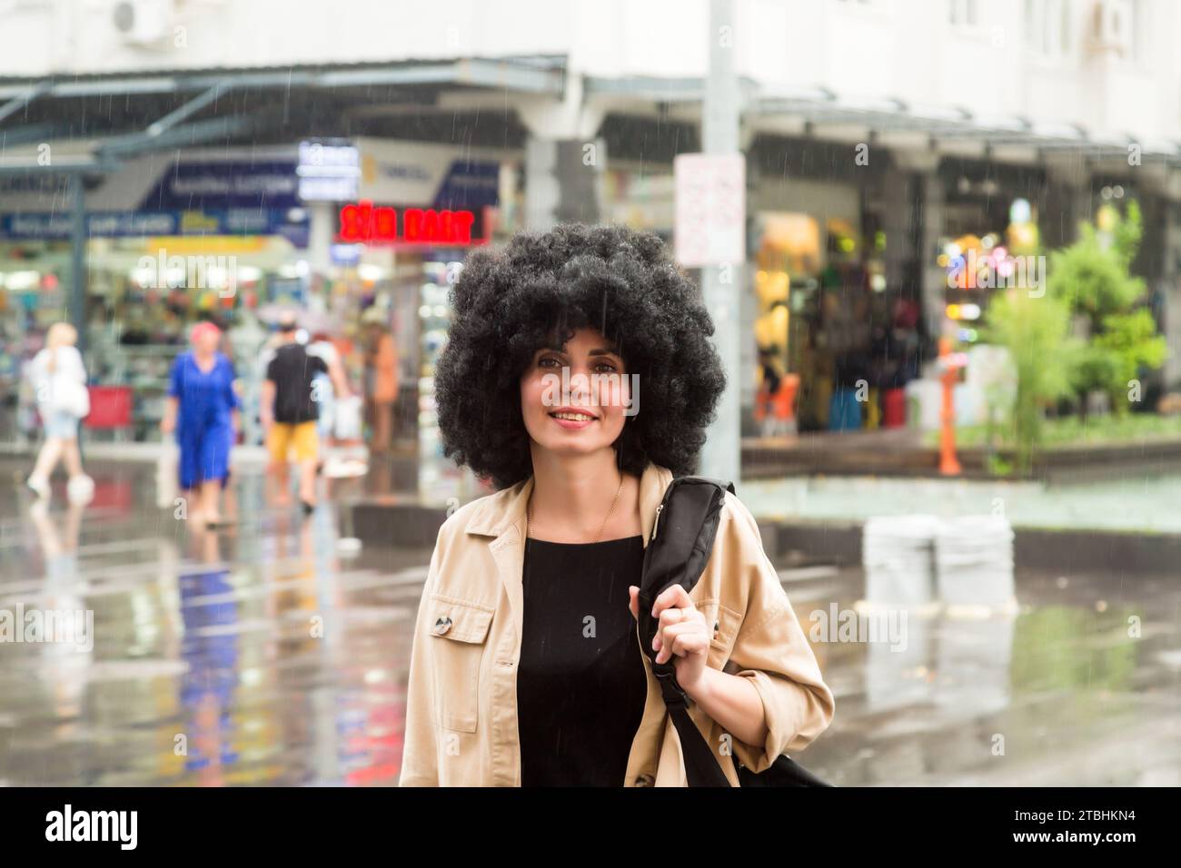 A woman in a short black dress walks quickly in the rain to avoid ...