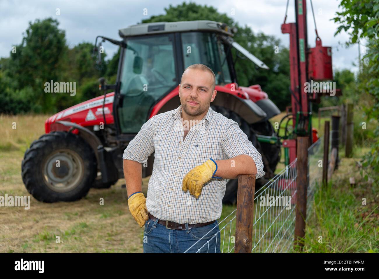 Fencing contractor with tools of his trade erecting a wire netting ...