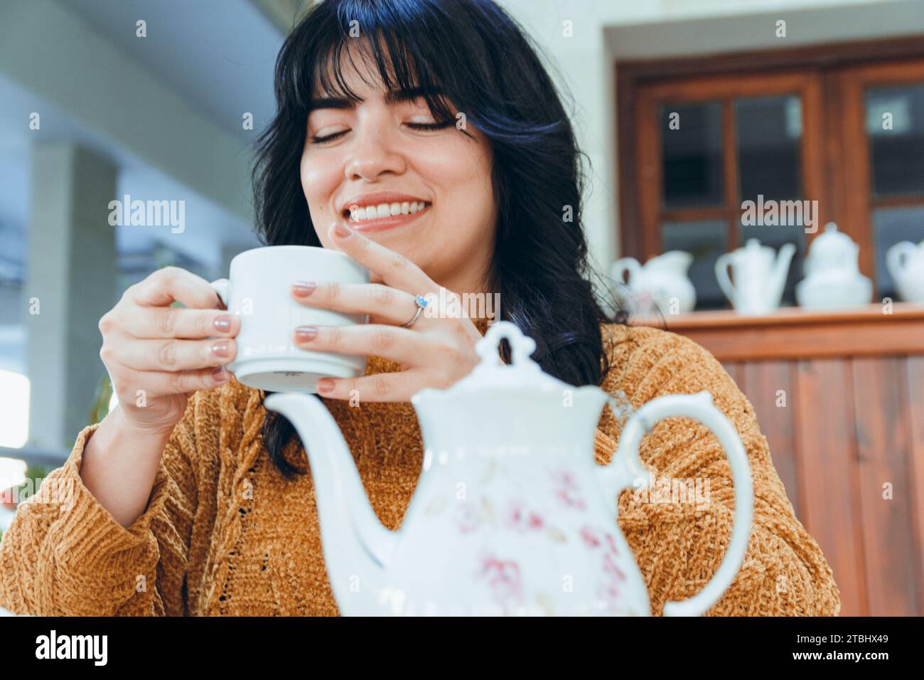 young black-haired Venezuelan woman happy smiling is sitting in restaurant enjoying day having ...