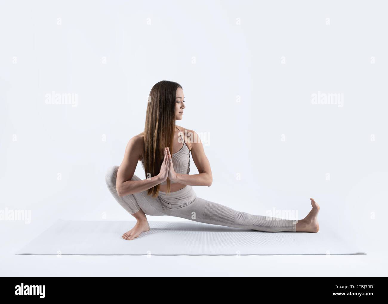 beautiful young athletic woman practicing yoga on a white mat with a ...