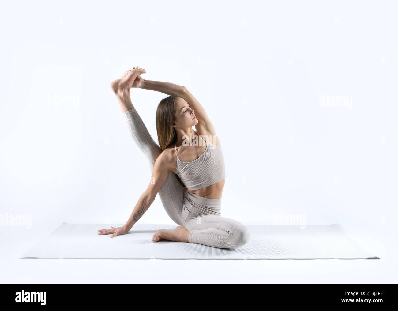 beautiful young athletic woman practicing yoga on a white mat with a ...