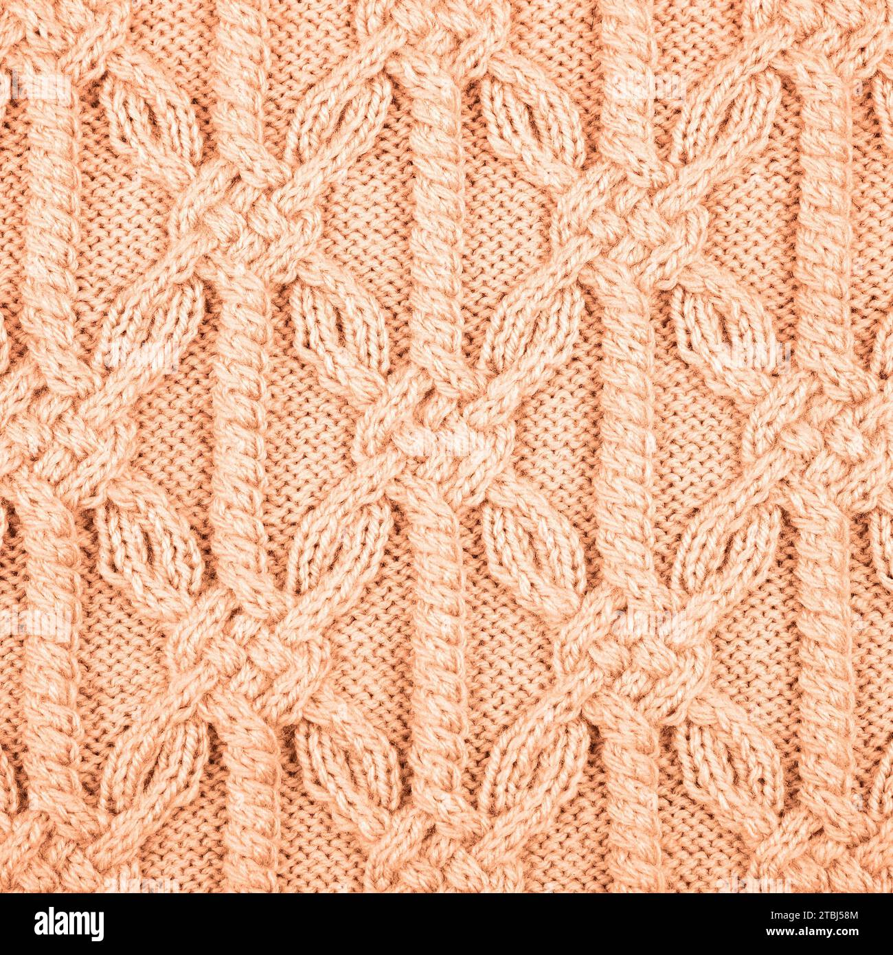 Knitted peach background. Large knitted fabric with a pattern. Close-up ...
