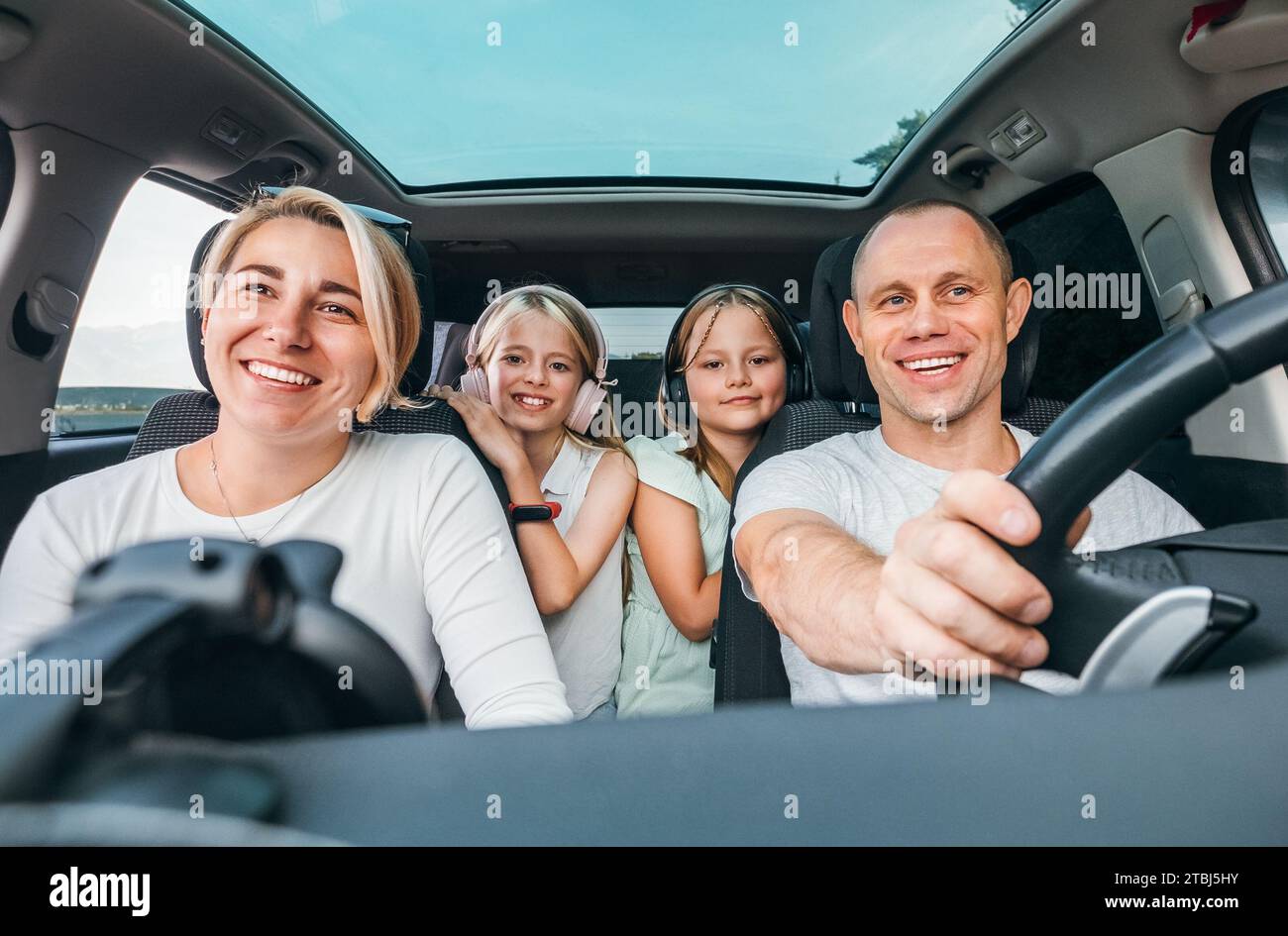 Happy young couple with two daughters inside car during auto trop. They ...