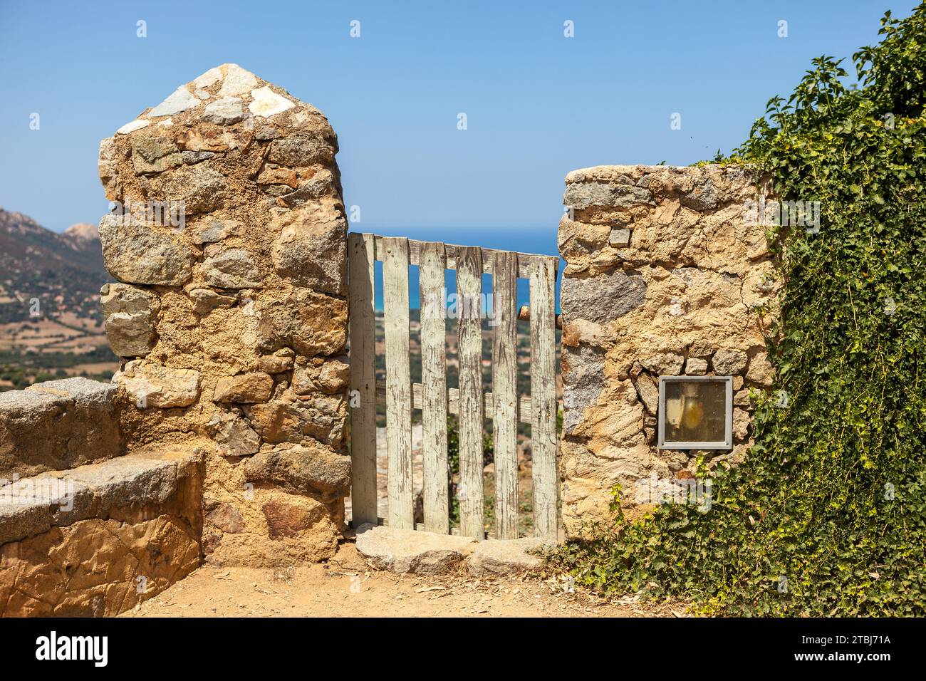 Stone wall and door of cleared boards in the village of Pigna, Balagne ...