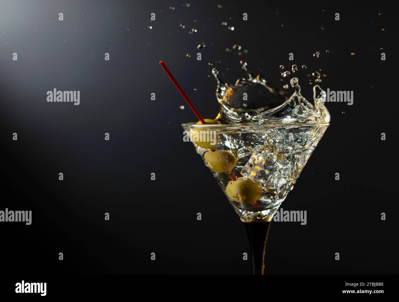 Glass of classic dry martini cocktail with green olives on a black ...