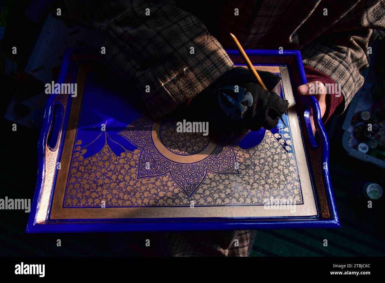 A Kashmiri artisan makes the final touches on a papier-mache product ...