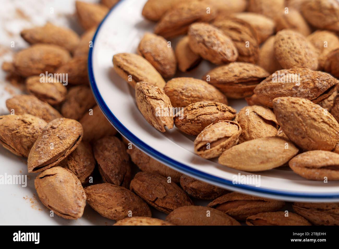 White ceramic dish with delicacy roasted almond nuts in cracked ...