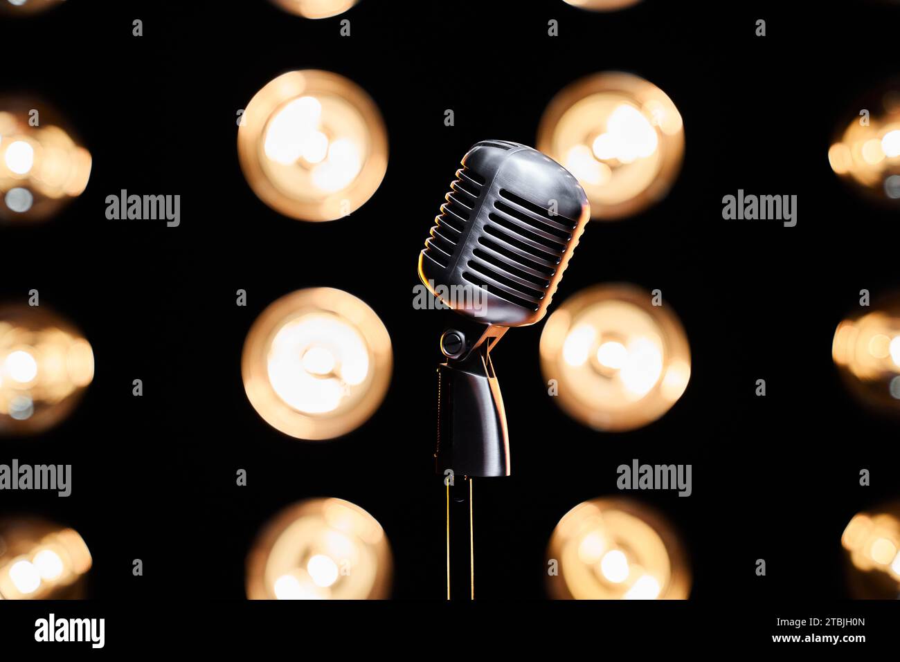 One retro microphone on empty stage with bulb lights on backdrop. Close ...