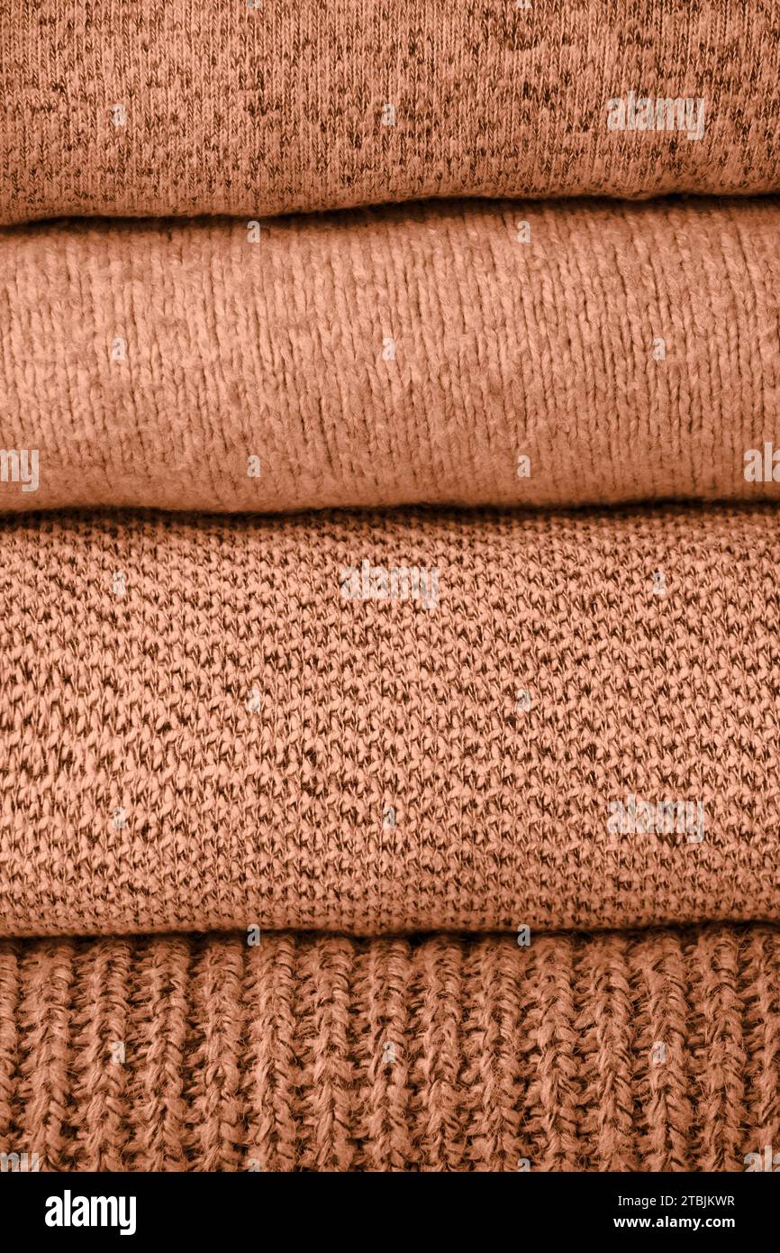 stack of warm knit sweaters on white table and gray background. Cold ...