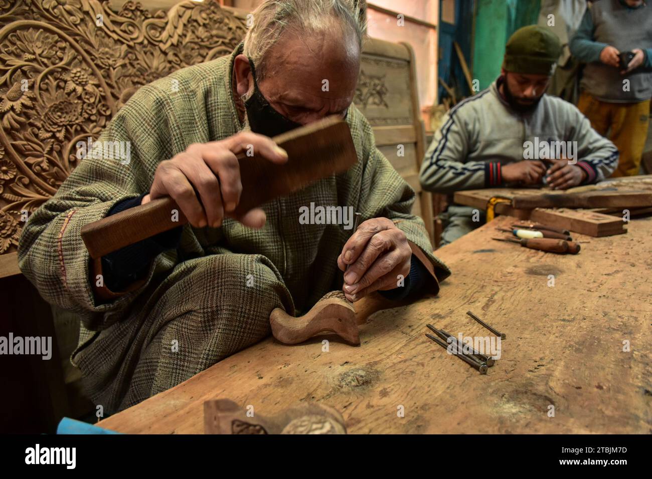 Kashmiri artisans carve a handicraft item at a wood carving factory ...