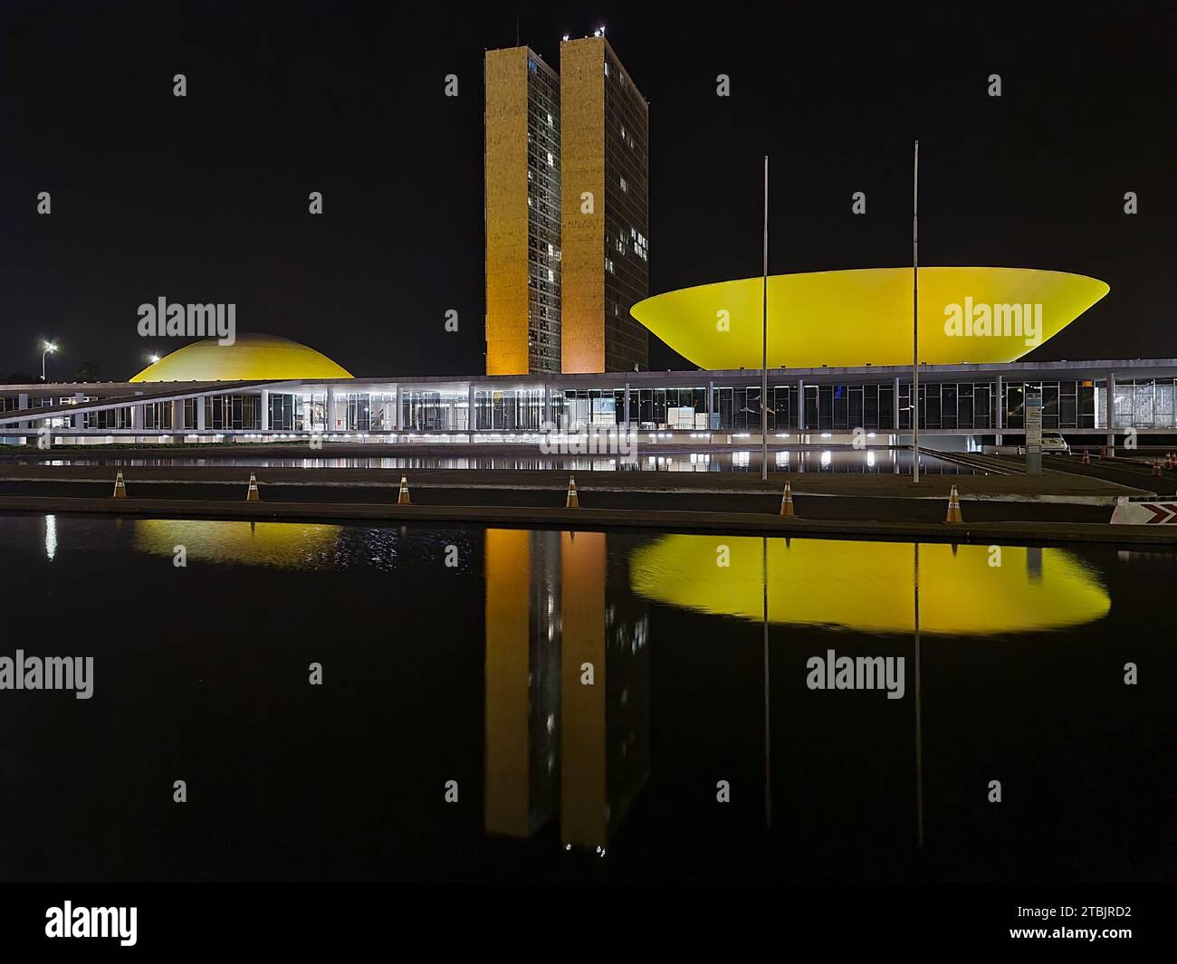 A majestic yellow skyscraper stands illuminated in the night sky near a ...
