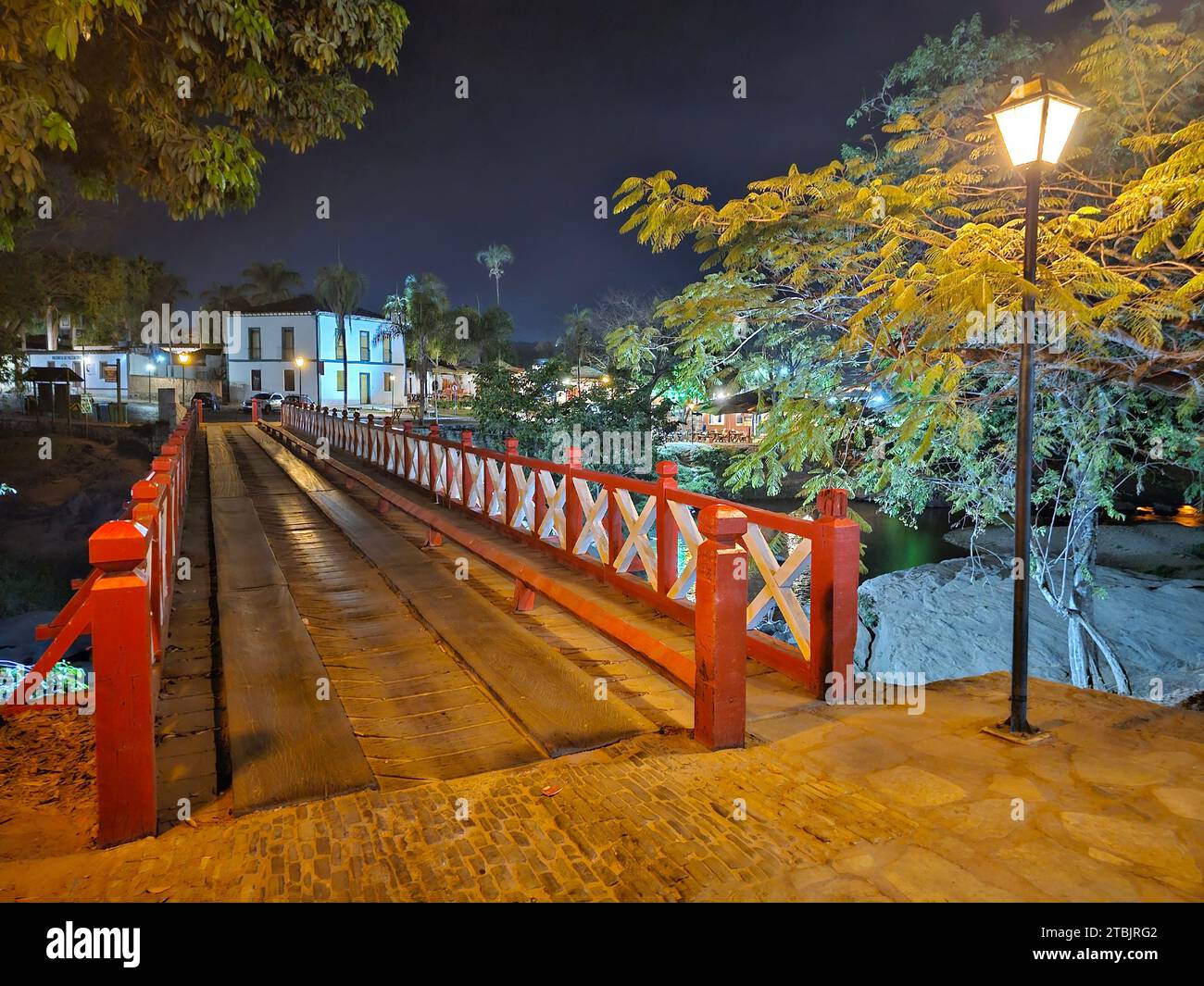 A stunning nighttime landscape of a red bridge that stretches across a ...