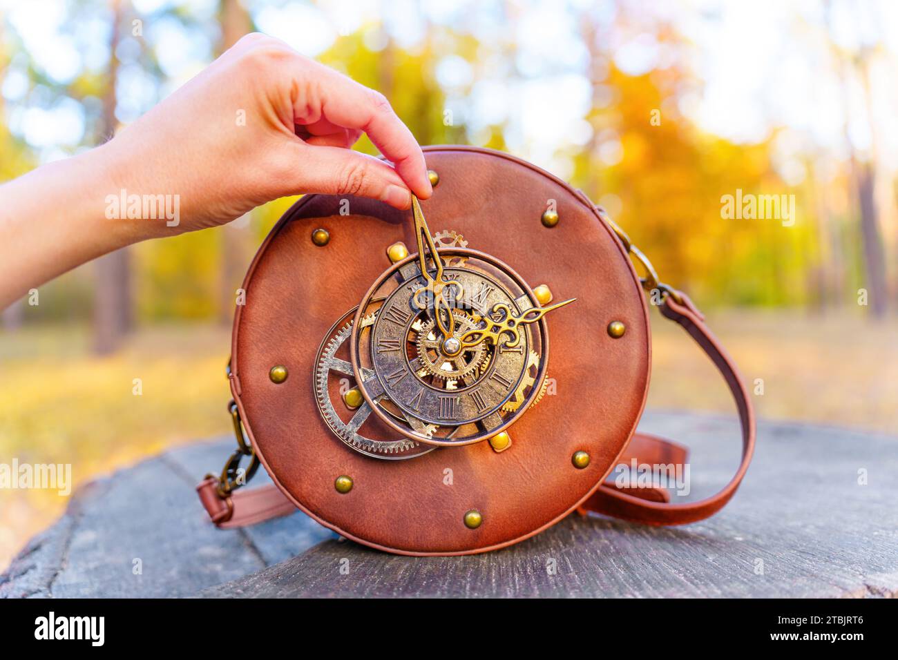 Hand delicately moves the clock hands on a stylish circle bag, adorned ...