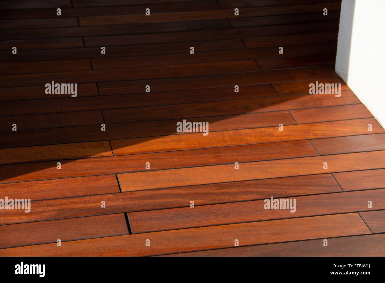 hardwood floor against white wall in sun light and shadow contrast ...