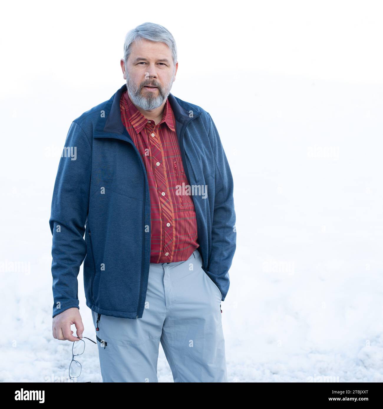 Man, 56 years, grey hair and beard, standing outside in winter with ...