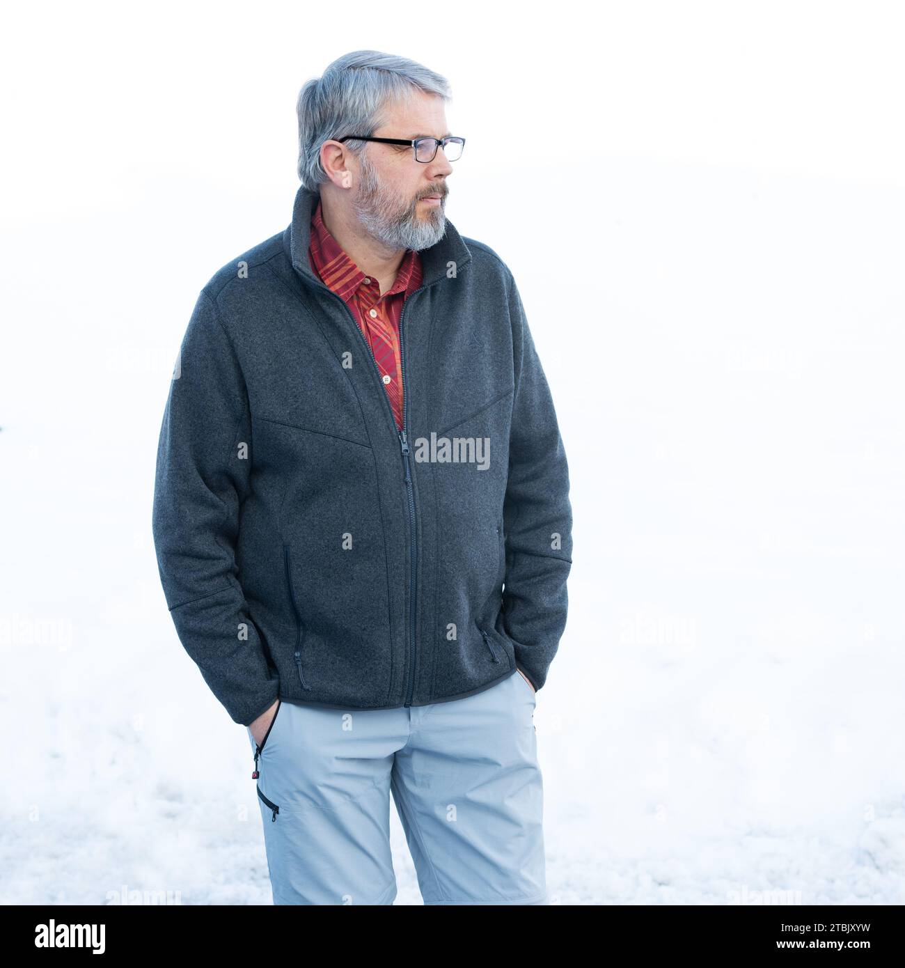 Man, 56 years, grey hair and beard, standing outside in winter with ...