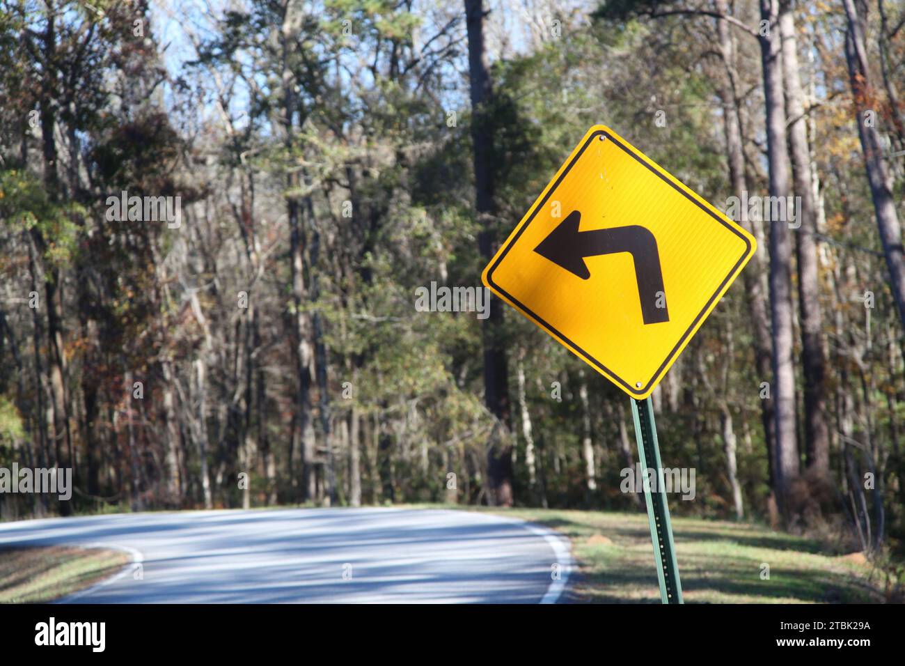 A yellow road sign of the left turn on a road Stock Photo - Alamy