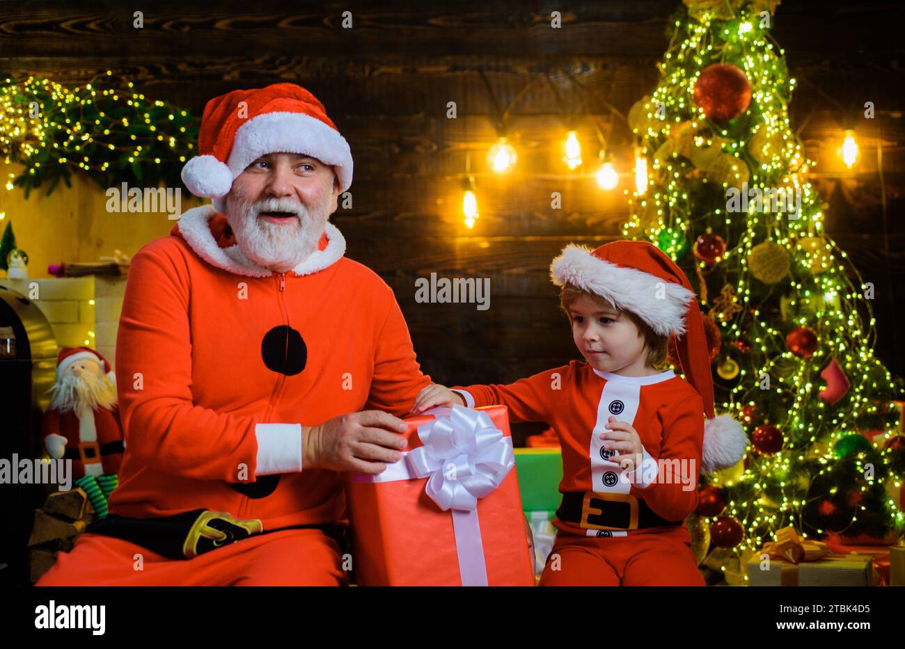 Santa Claus and Santa child boy at home with Christmas gift. Happy ...