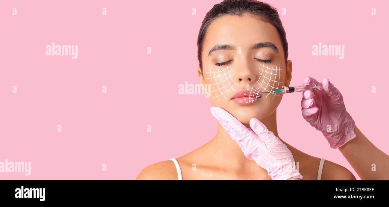 Young woman receiving filler injection in face against pink background ...
